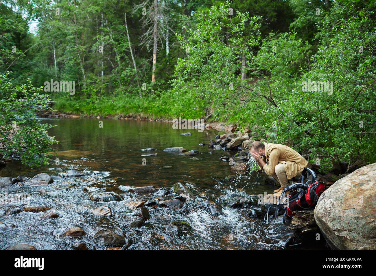 Young man washing up his face in the river Stock Photo - Alamy