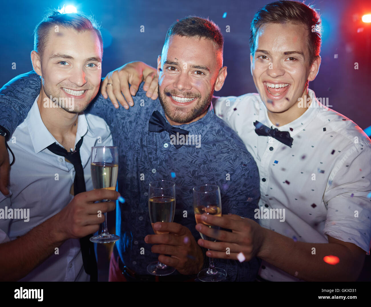 Three elegant guys with champagne looking at camera at party Stock ...