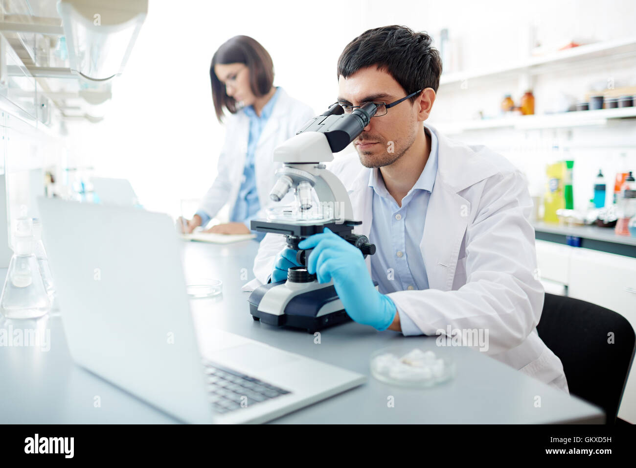 Lab worker looking in microscope at work Stock Photo - Alamy