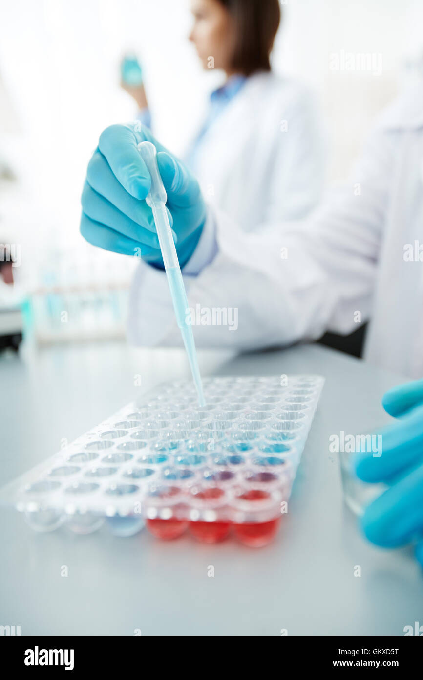Gloved hand holding dropper with liquid substance Stock Photo - Alamy