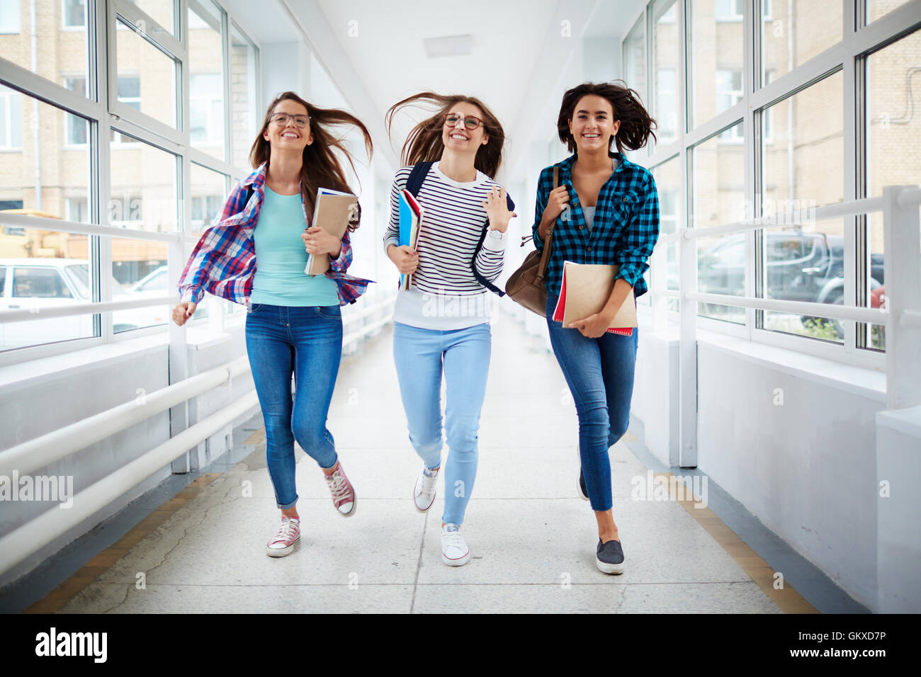 Three hurrying girls running for college class Stock Photo - Alamy