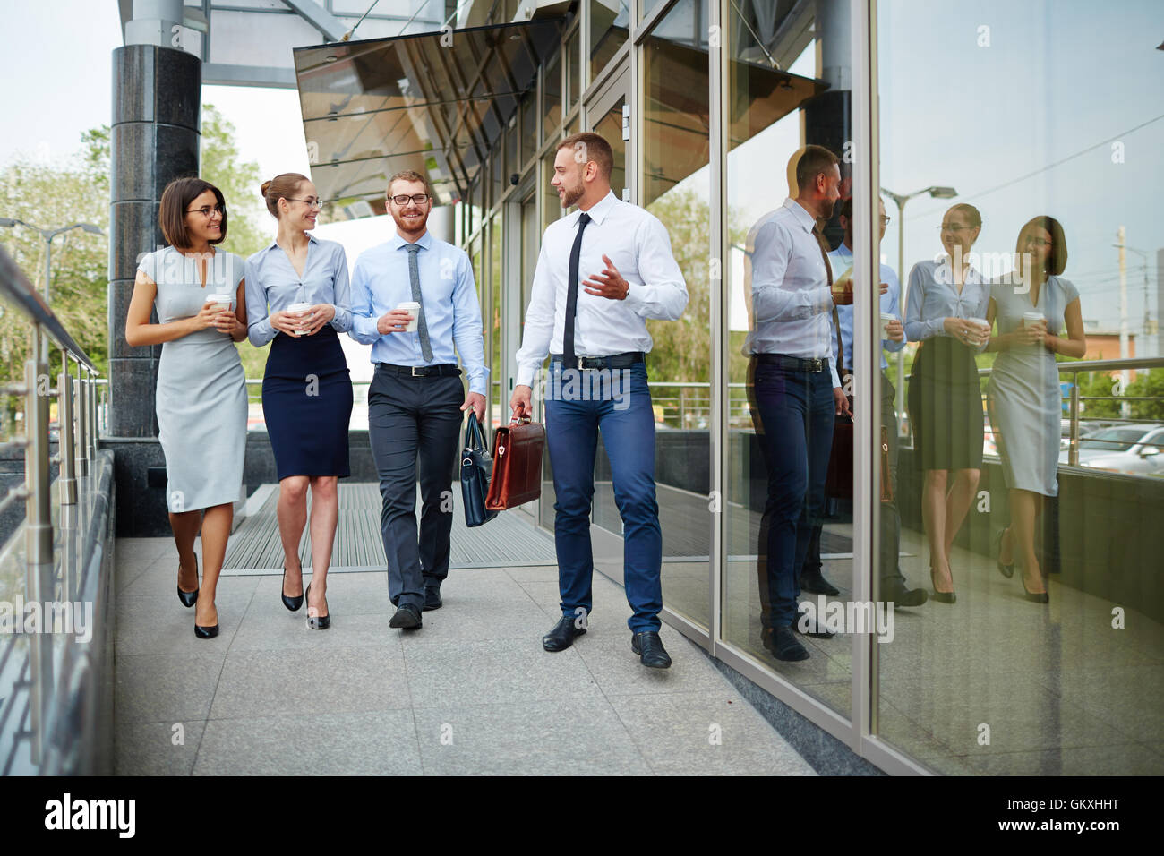 Group of white collar workers walking along modern building Stock Photo ...