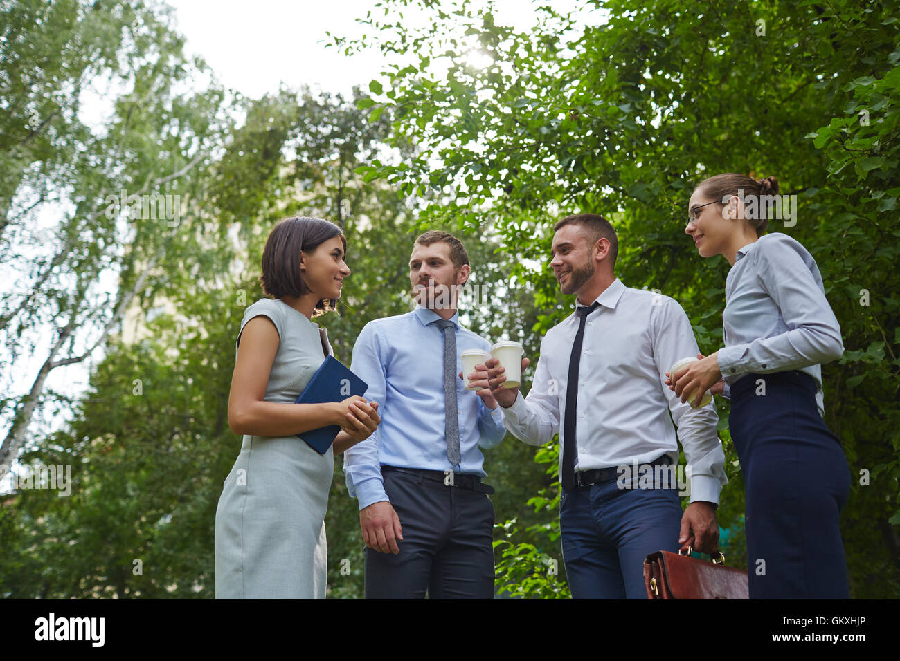 Happy colleagues talking at break in park Stock Photo - Alamy