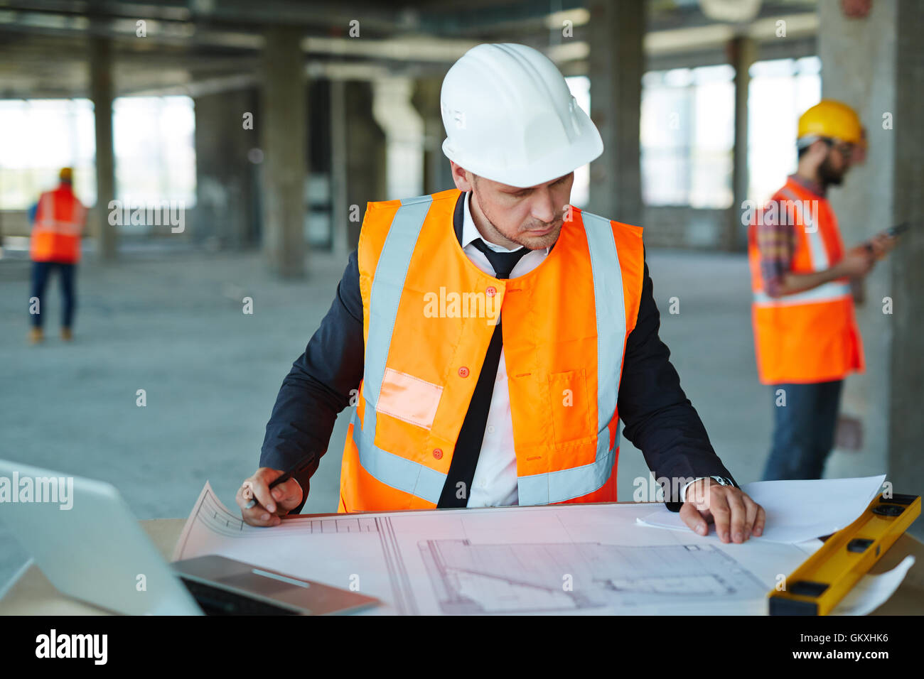 Constructor in uniform and helmet looking at sketch Stock Photo - Alamy
