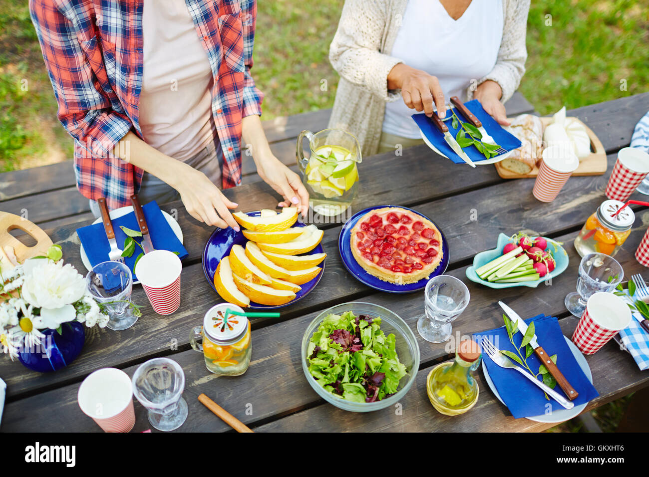 Human hands during preparation of food and serving table for picnic ...