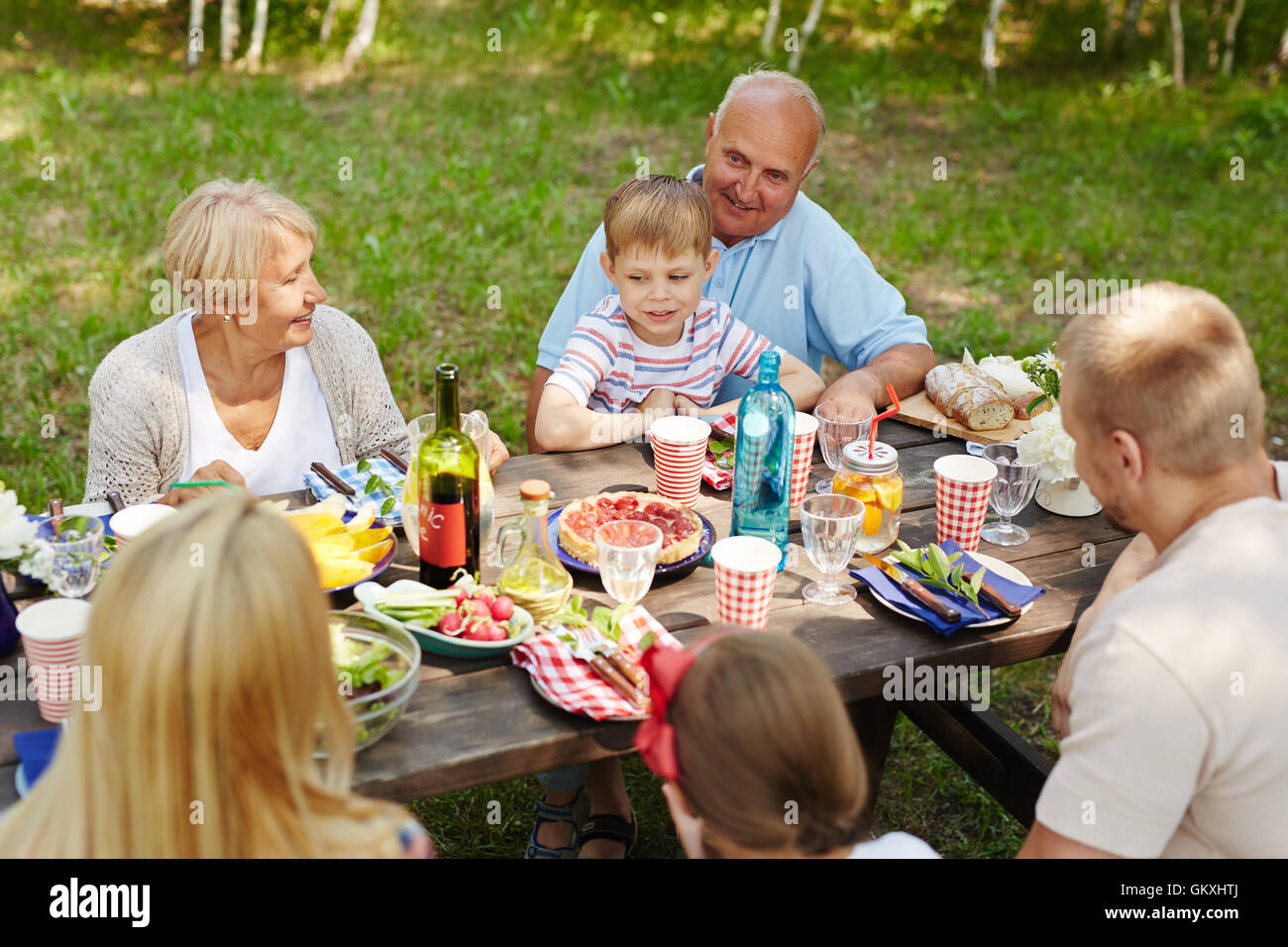 Big family sitting by table outdoors Stock Photo - Alamy