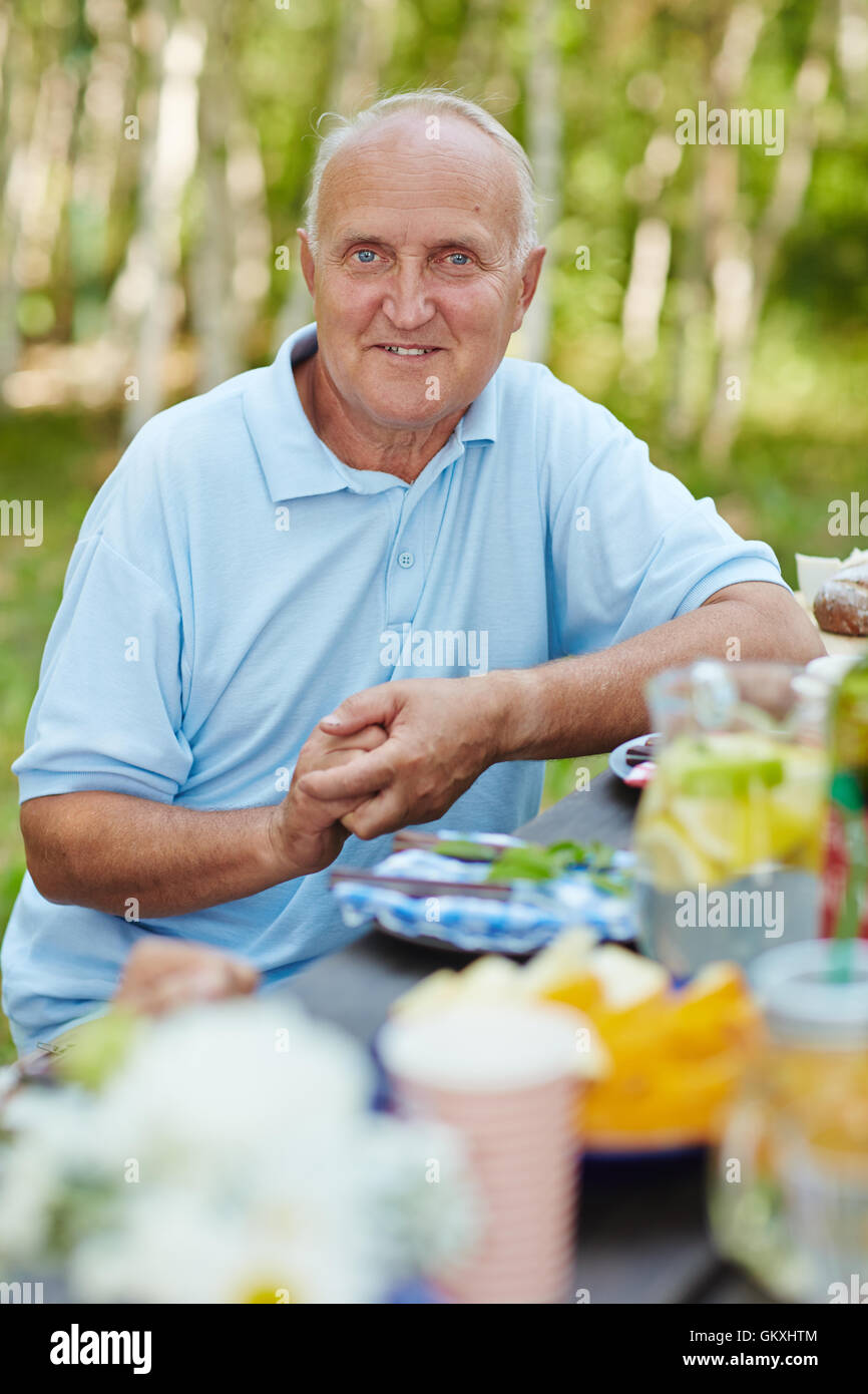 Happy senior man looking at camera by dinner table Stock Photo - Alamy