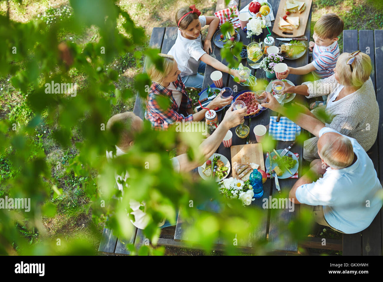 Family members gathered by dinner table outdoors Stock Photo - Alamy