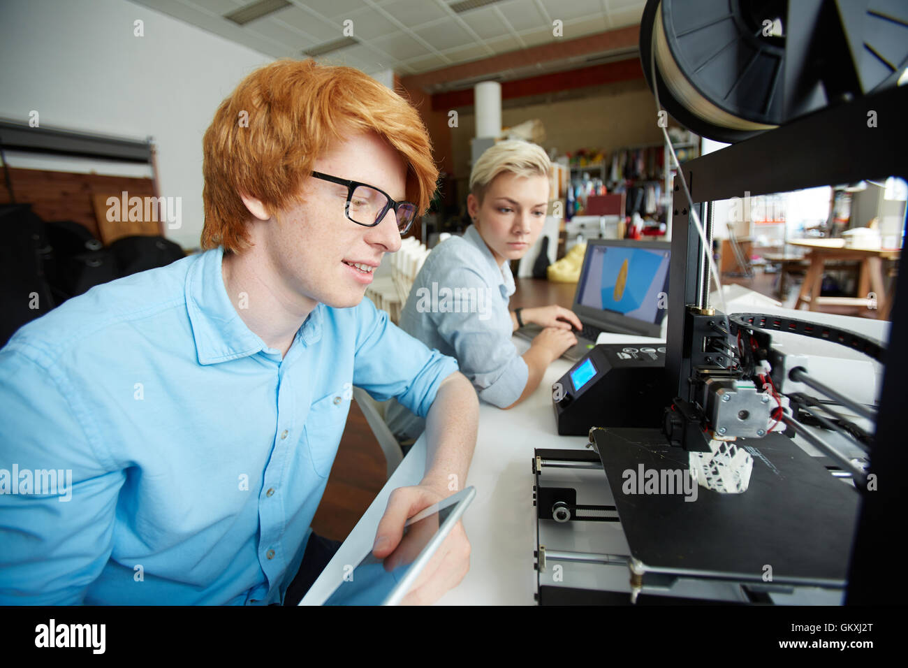 Handsome designer looking at new architectural model in 3d printer ...