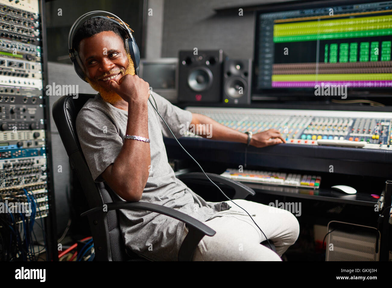 Happy young African man sitting in audio studio Stock Photo - Alamy