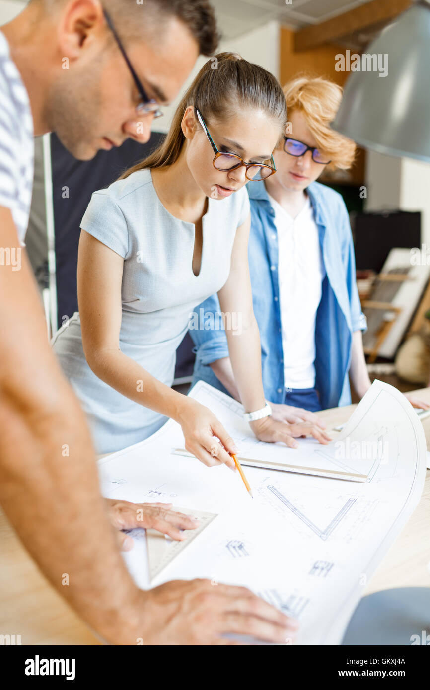 Female architect explaining details of sketch to co-workers Stock Photo ...