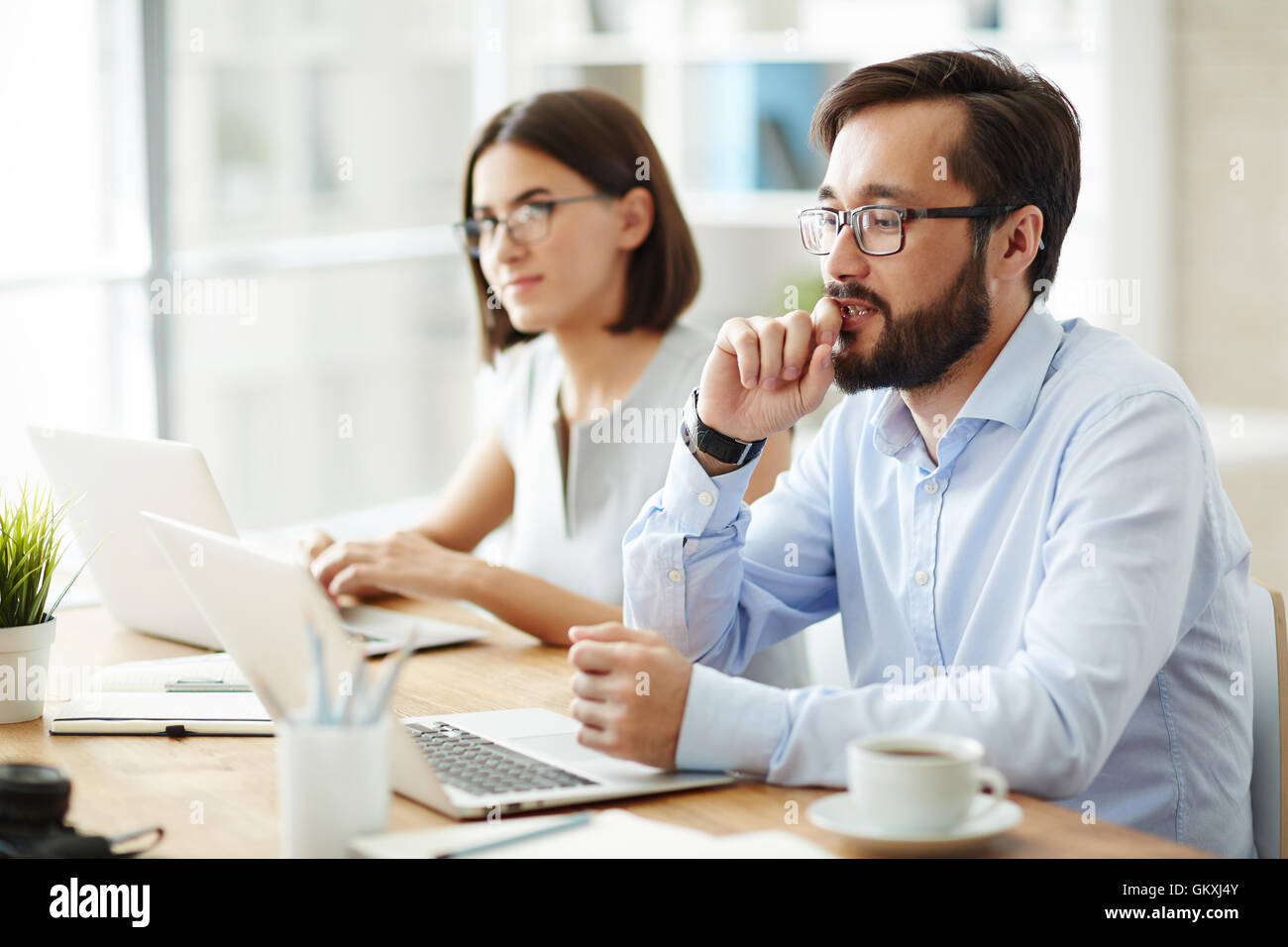 Pensive employee looking at laptop display during work Stock Photo - Alamy