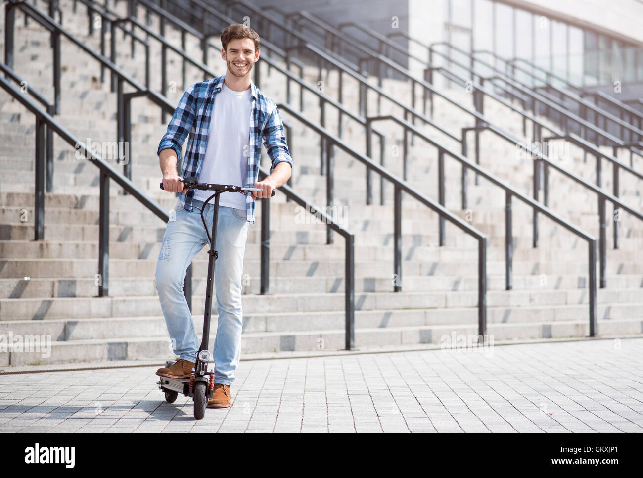 Joyful handsome man riding a scooter Stock Photo - Alamy