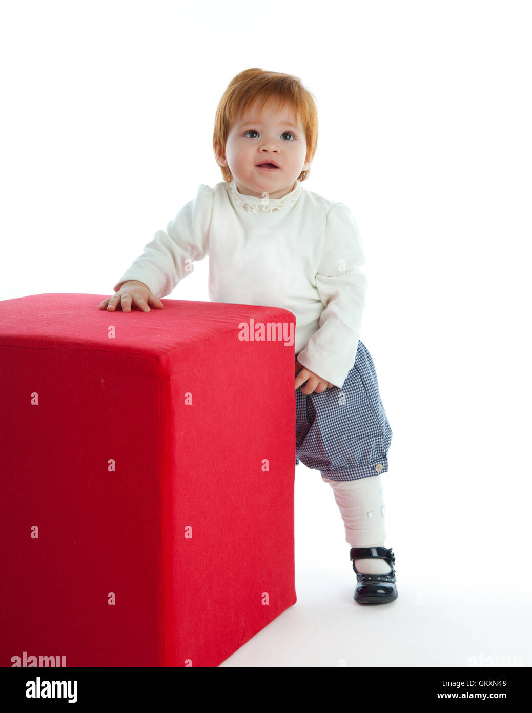 Cute toddler playing with a red cube on white background Stock Photo ...
