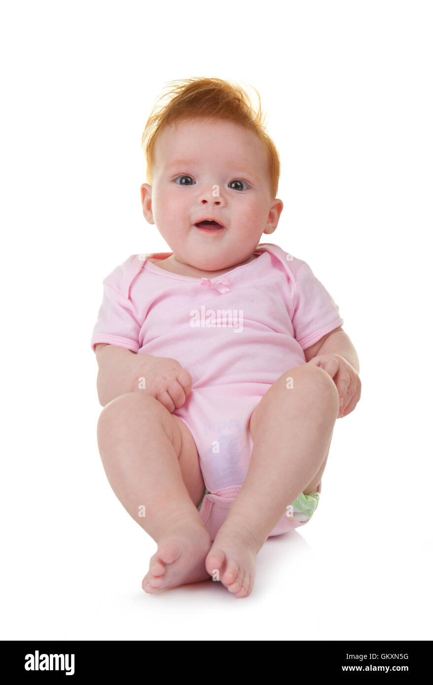 Smiling baby in pink jumpsuit sitting on the floor isolated on white ...