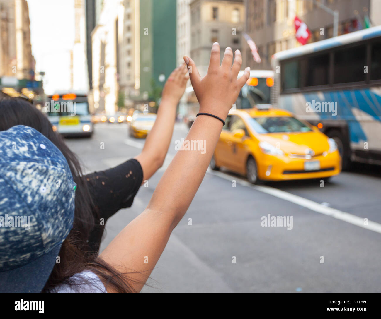 Tourists call a yellow cab in Manhattan with typical gesture with arm ...