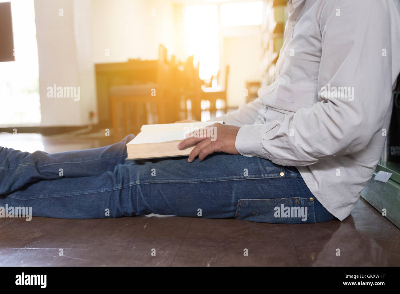 man sitting and reading book on floor in aisle in library Stock Photo ...