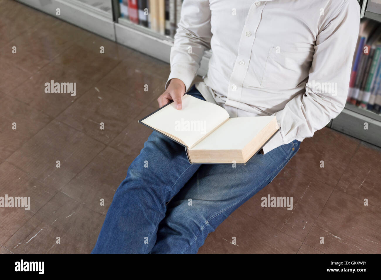 man sitting and reading book on floor in aisle in library Stock Photo ...