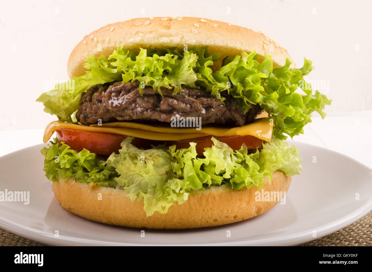 home made beef hamburger, salad, sliced cheese and tomato slices on a ...