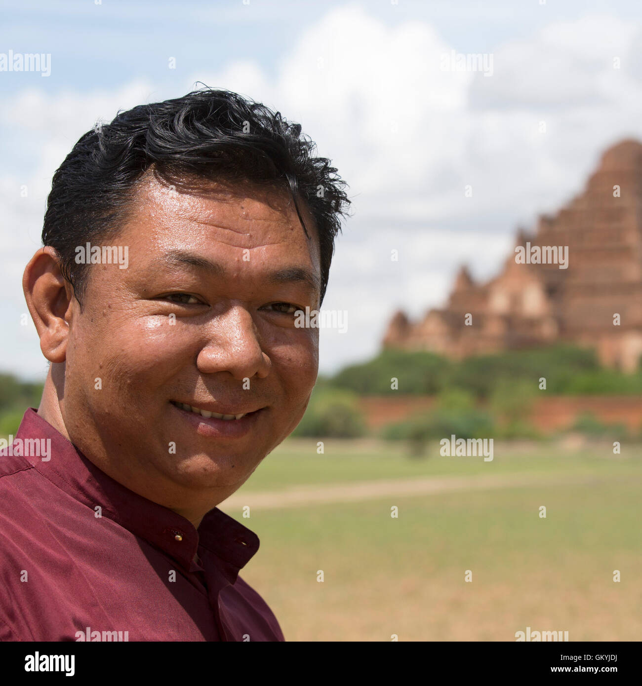 A Burmese man at Bagan, Myanmar (Burma). The man stands in front one of ...
