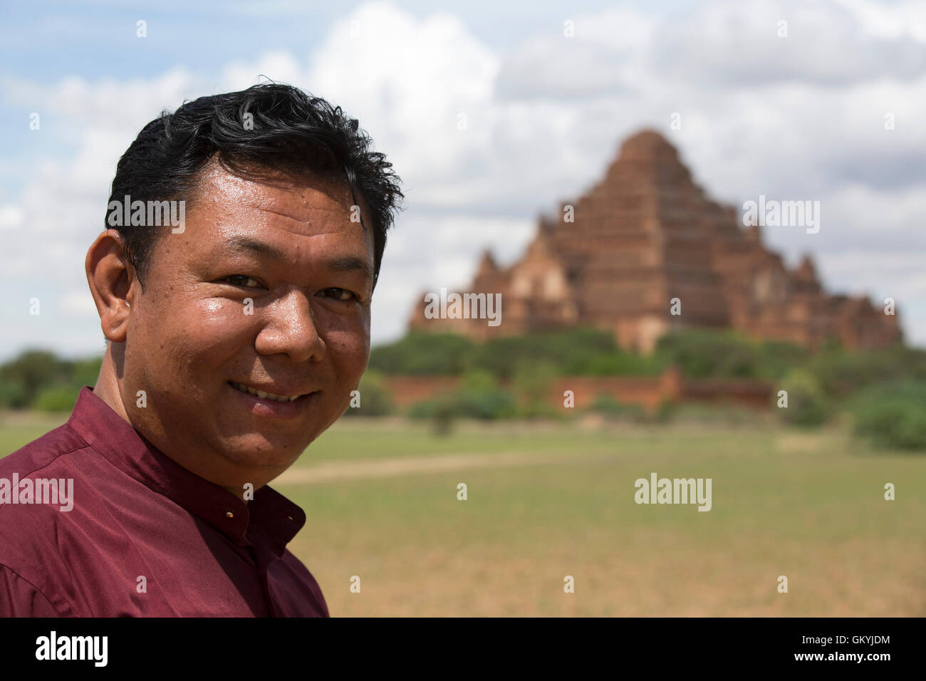 A Burmese man at Bagan, Myanmar (Burma). The man stands in front one of ...