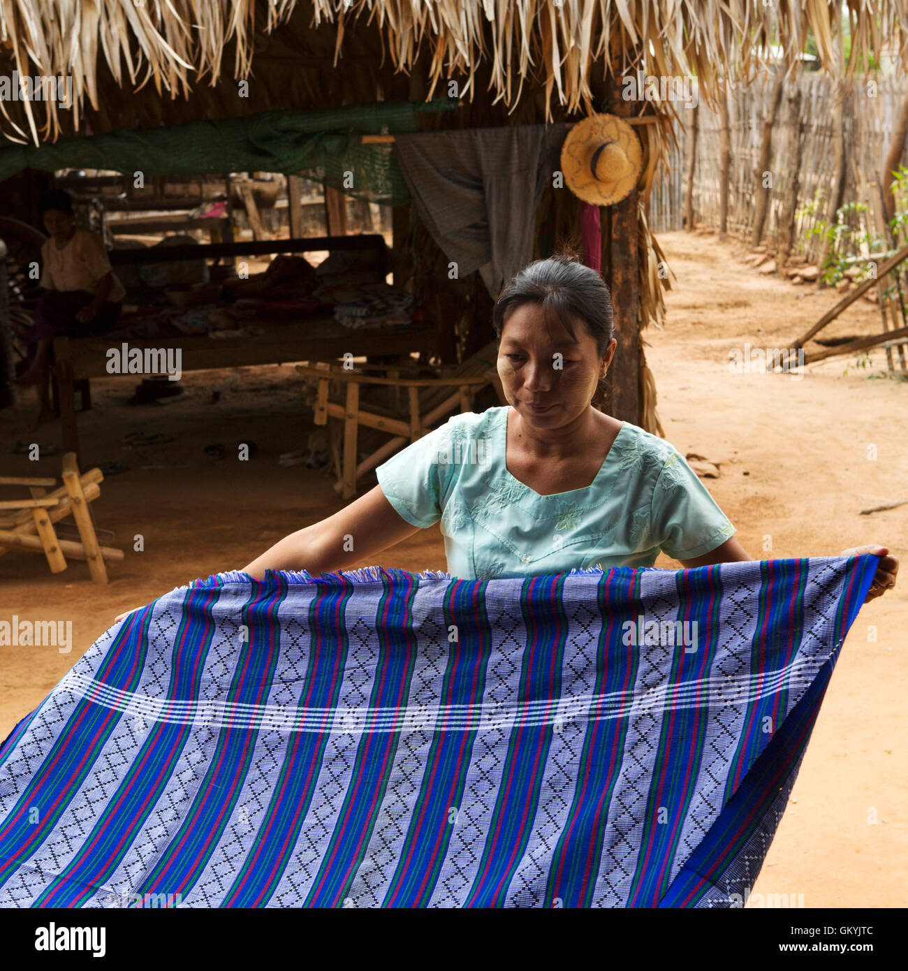 A Burmese woman displays cloth she has woven at her house in Minnathu ...