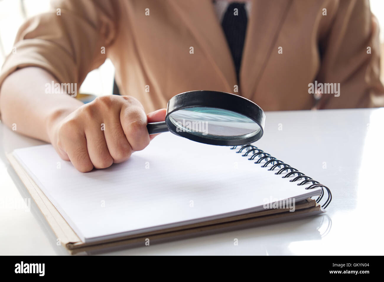 Businesswoman looking through a magnifying glass to documents note ...