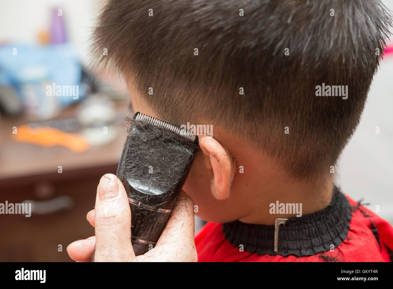 professional hairdresser doing hair cutting for a boy Stock Photo - Alamy