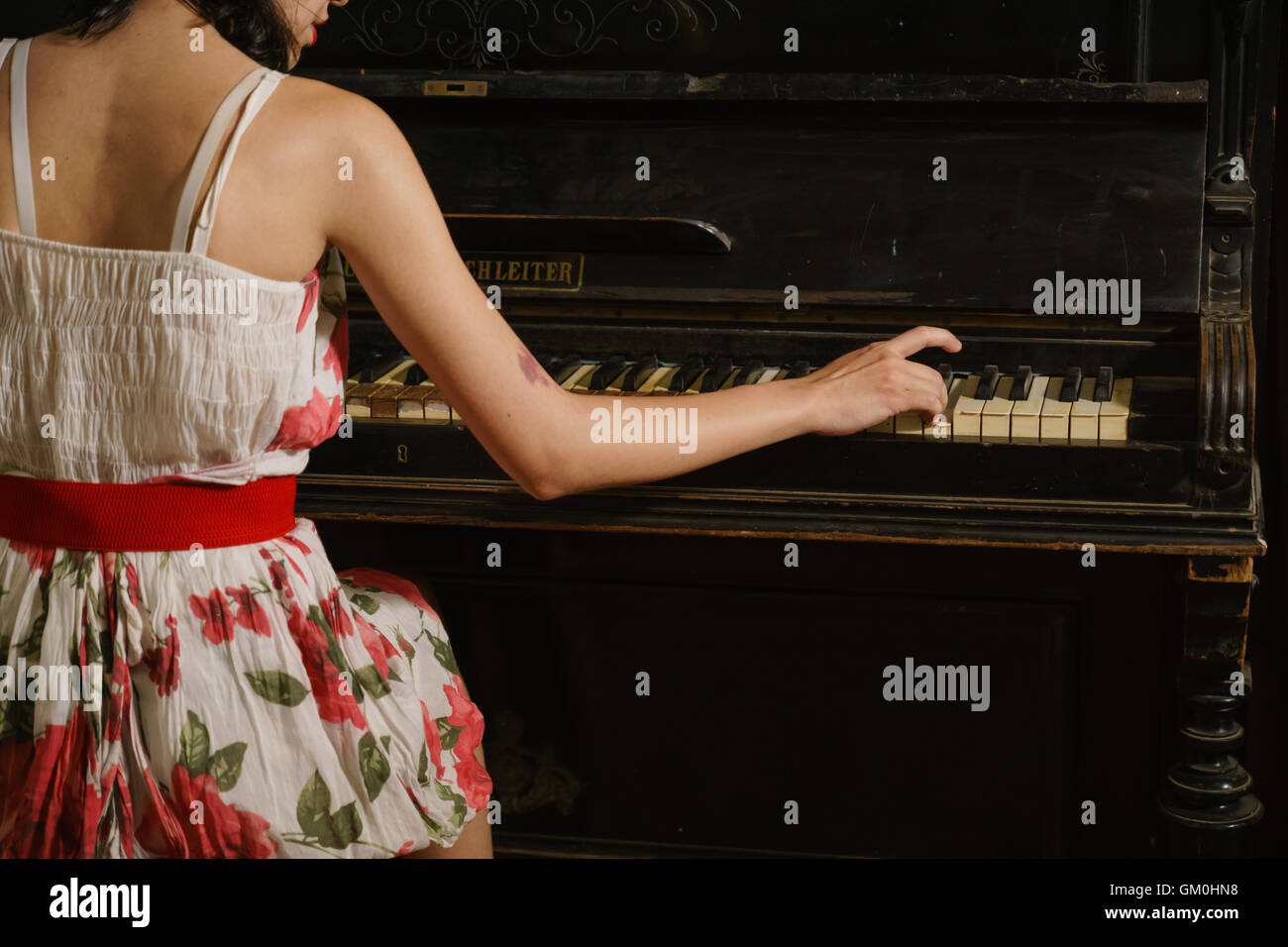 pretty dark-haired girl is playing on the black piano Stock Photo - Alamy