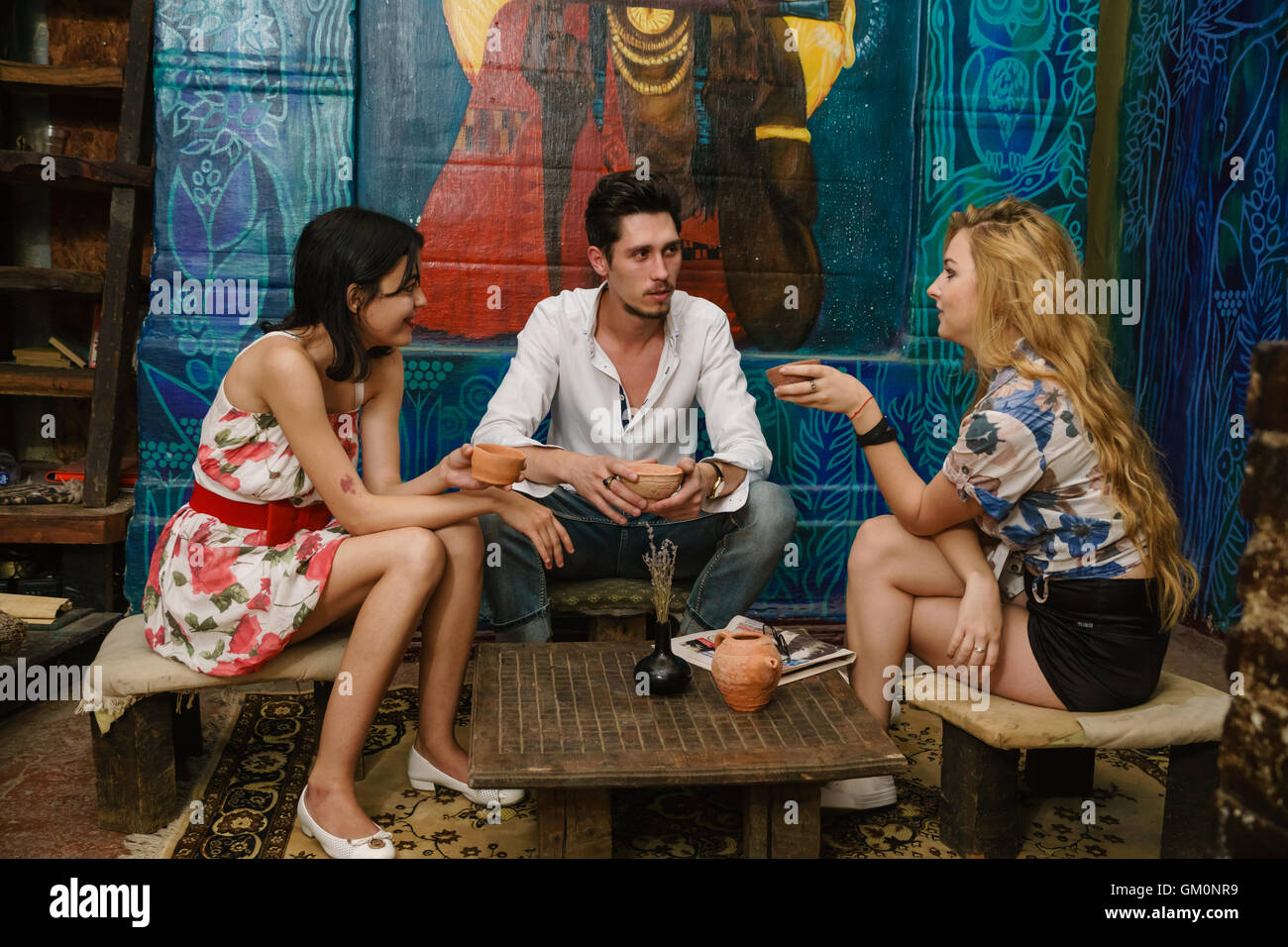 group of young people communicates during tea party in the room in ...
