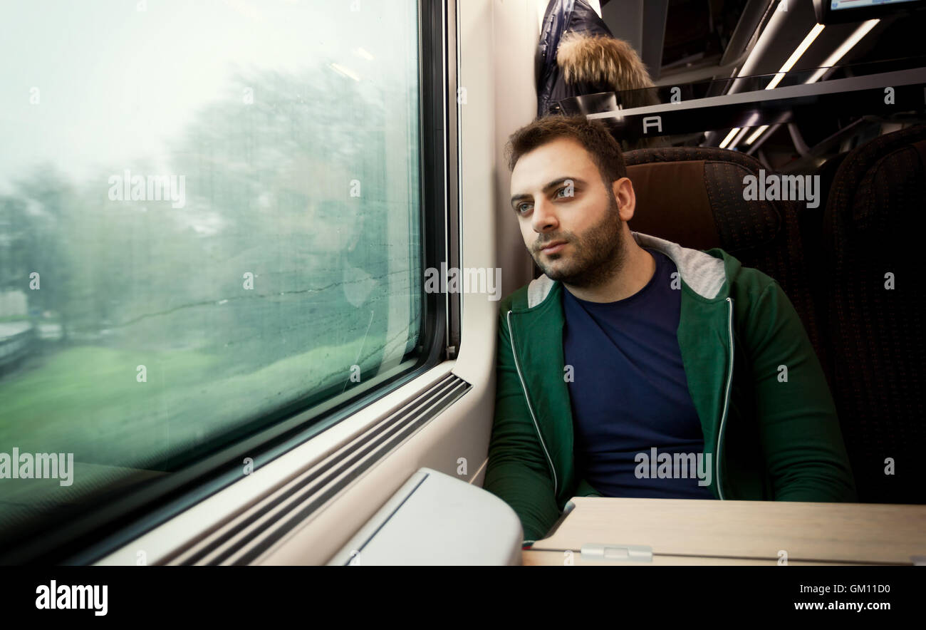 Young man staring out the train window on a rainy and grey day Stock ...