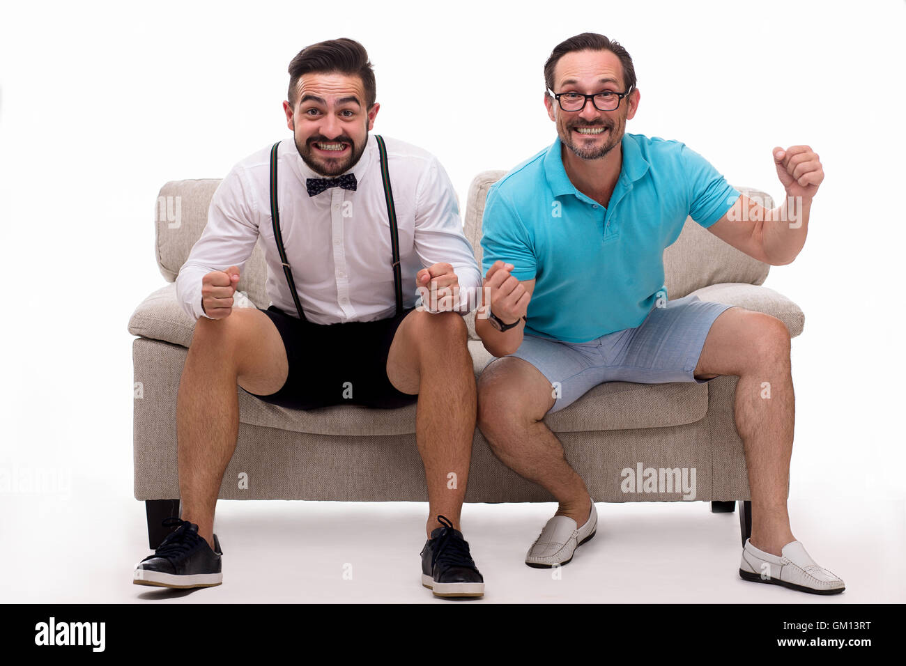 Two excited men sitting on couch Stock Photo - Alamy