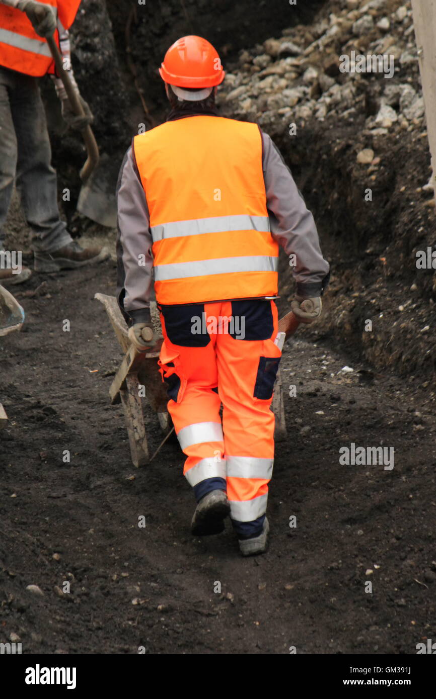 Workers pushing wheelbarrow Stock Photo - Alamy