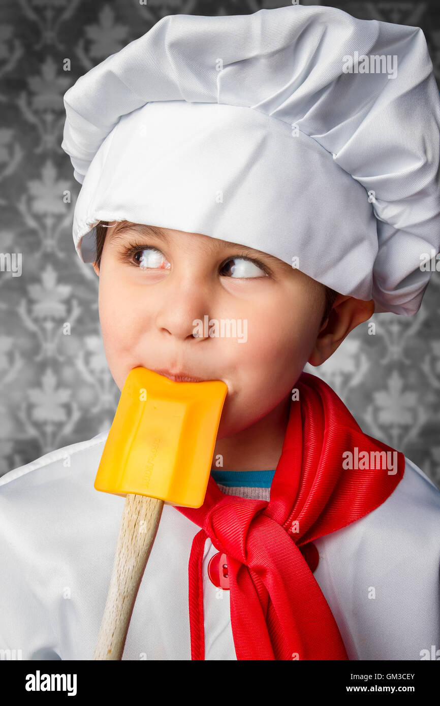 A little boy cook in uniform over vintage background playing wi Stock ...