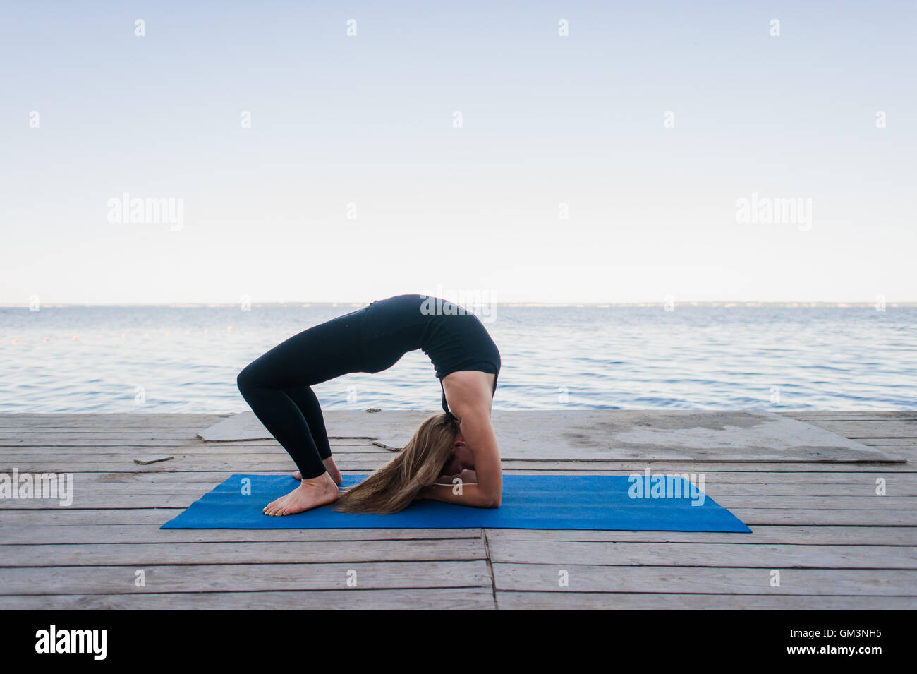 Beautiful sporty fit blond young woman in black sportswear working out ...