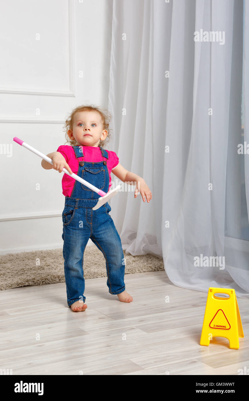 Little girl is cleaned with a mop in his hands. Small mother's helper ...