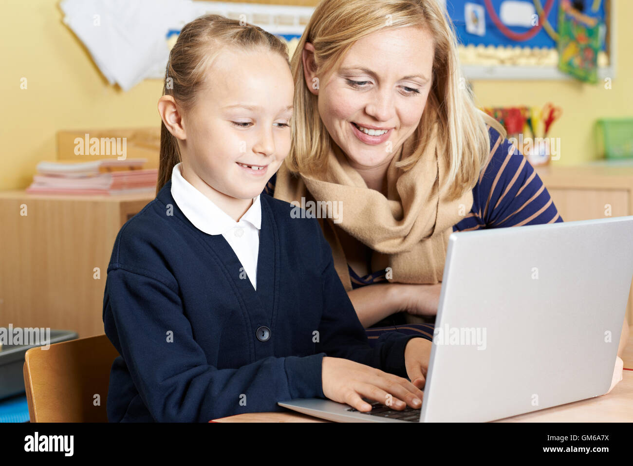 Teacher Helping Female Elementary School Pupil In Computer Class Stock ...