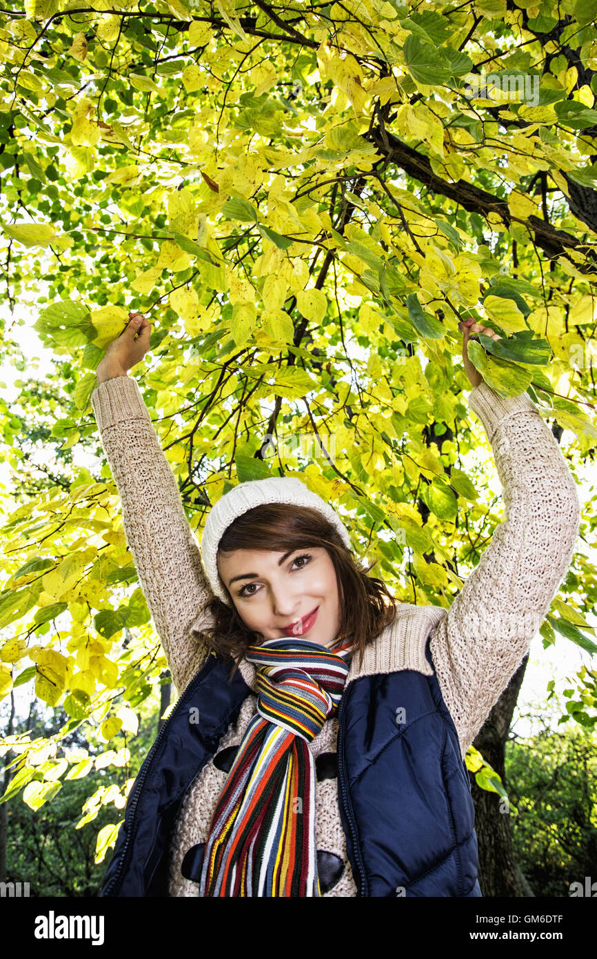 Beautiful smiling brunette woman posing under the beech tree in autumn ...