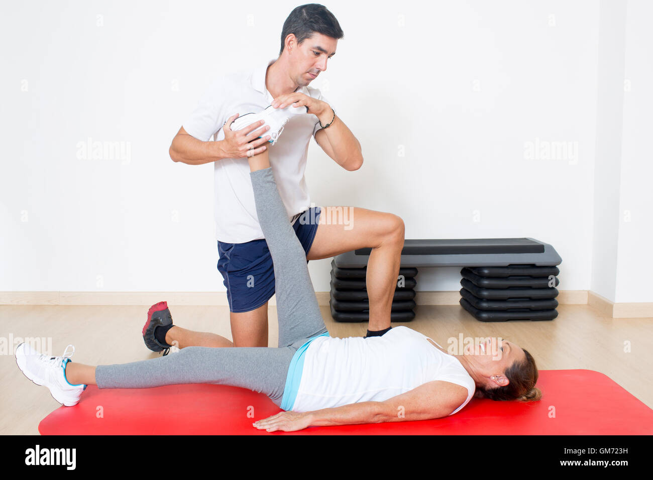 Personal trainer helping with stretching exercise Stock Photo - Alamy