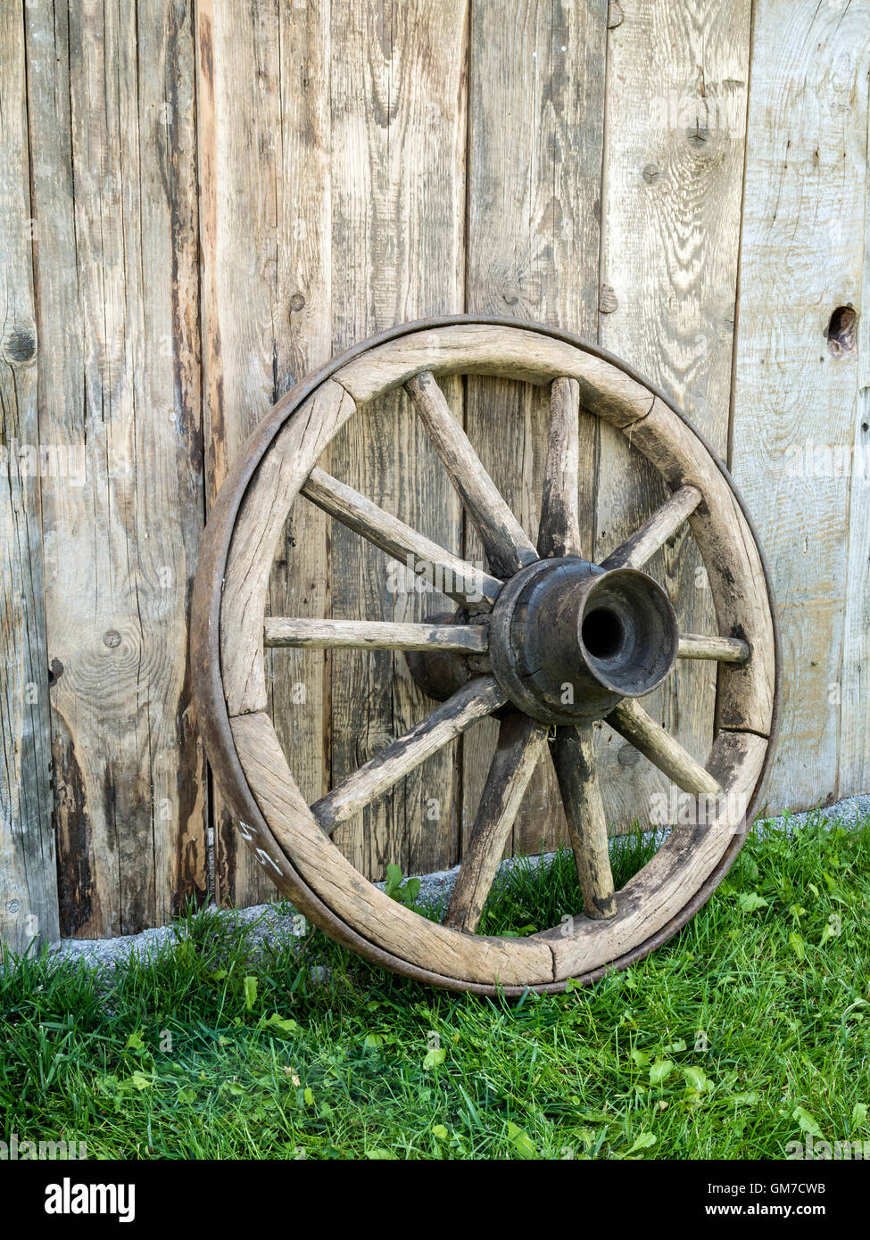 Old wooden wagon wheel resting against rustic wooden fence Stock Photo ...