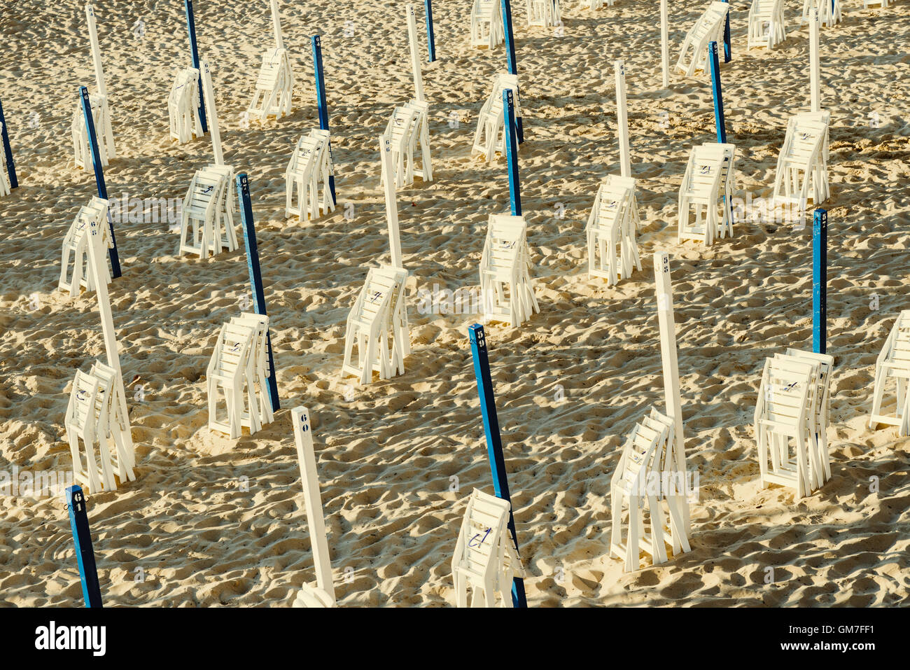 Rows of white plastic chairs and posts for awnings on sandy beach Stock ...