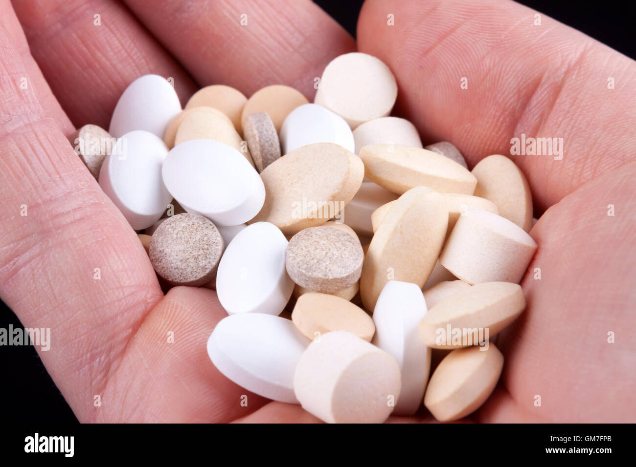 Hands full of pils on black background Stock Photo - Alamy