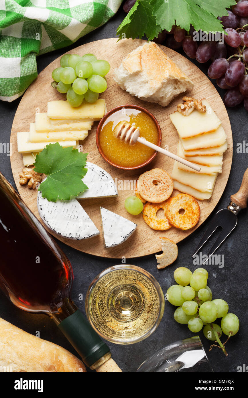 White wine, grape, bread, cheese plate and honey on stone table. Top ...