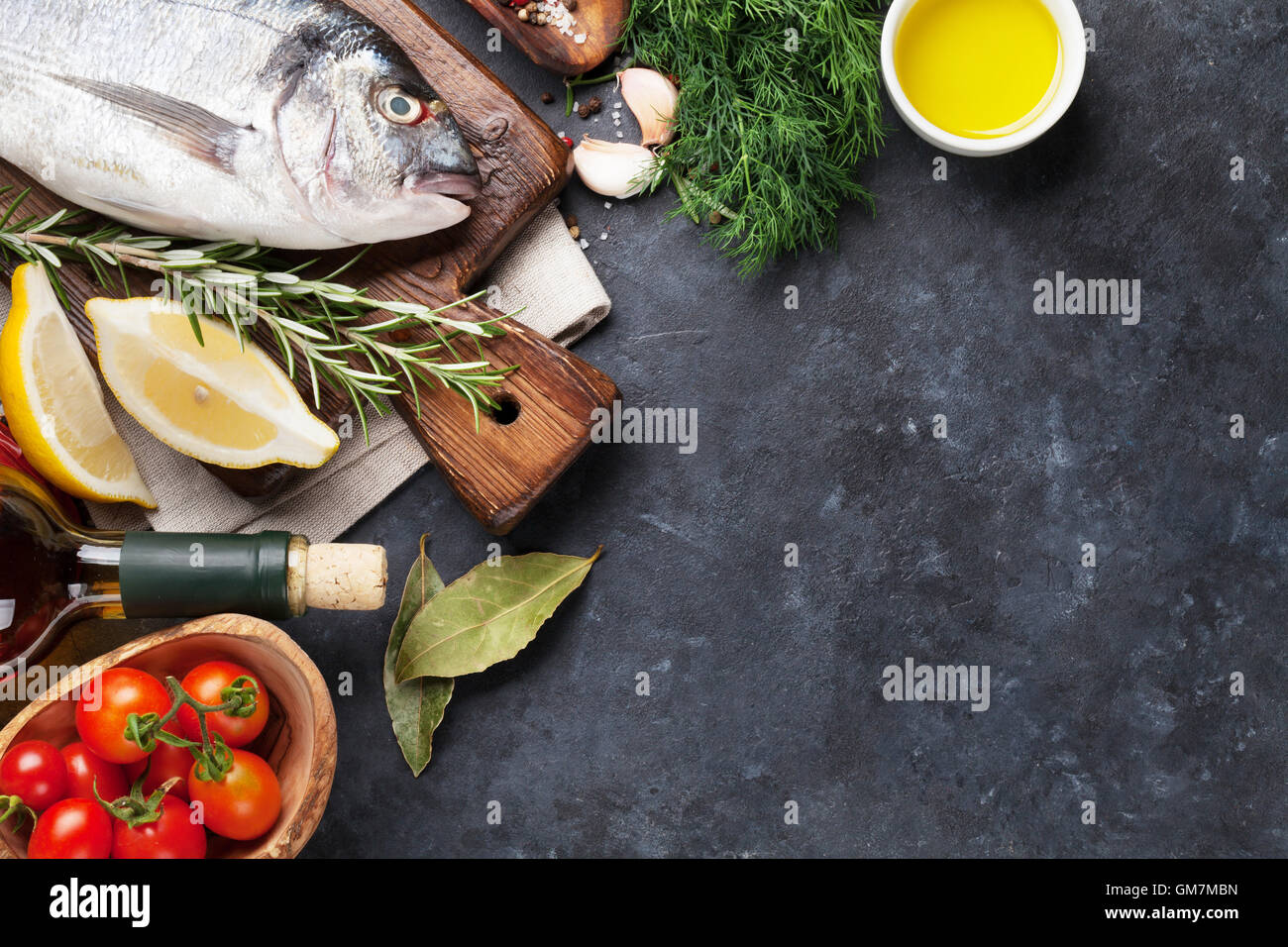 Raw fish cooking and ingredients. White wine, dorado, lemon, herbs and ...