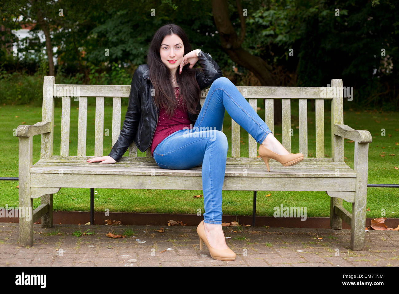 young woman sitting on a park bench posing Stock Photo - Alamy