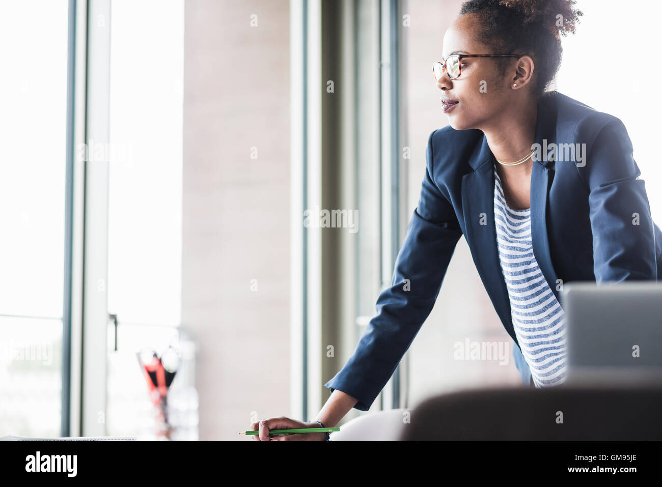 Businesswoman in office looking through window Stock Photo - Alamy