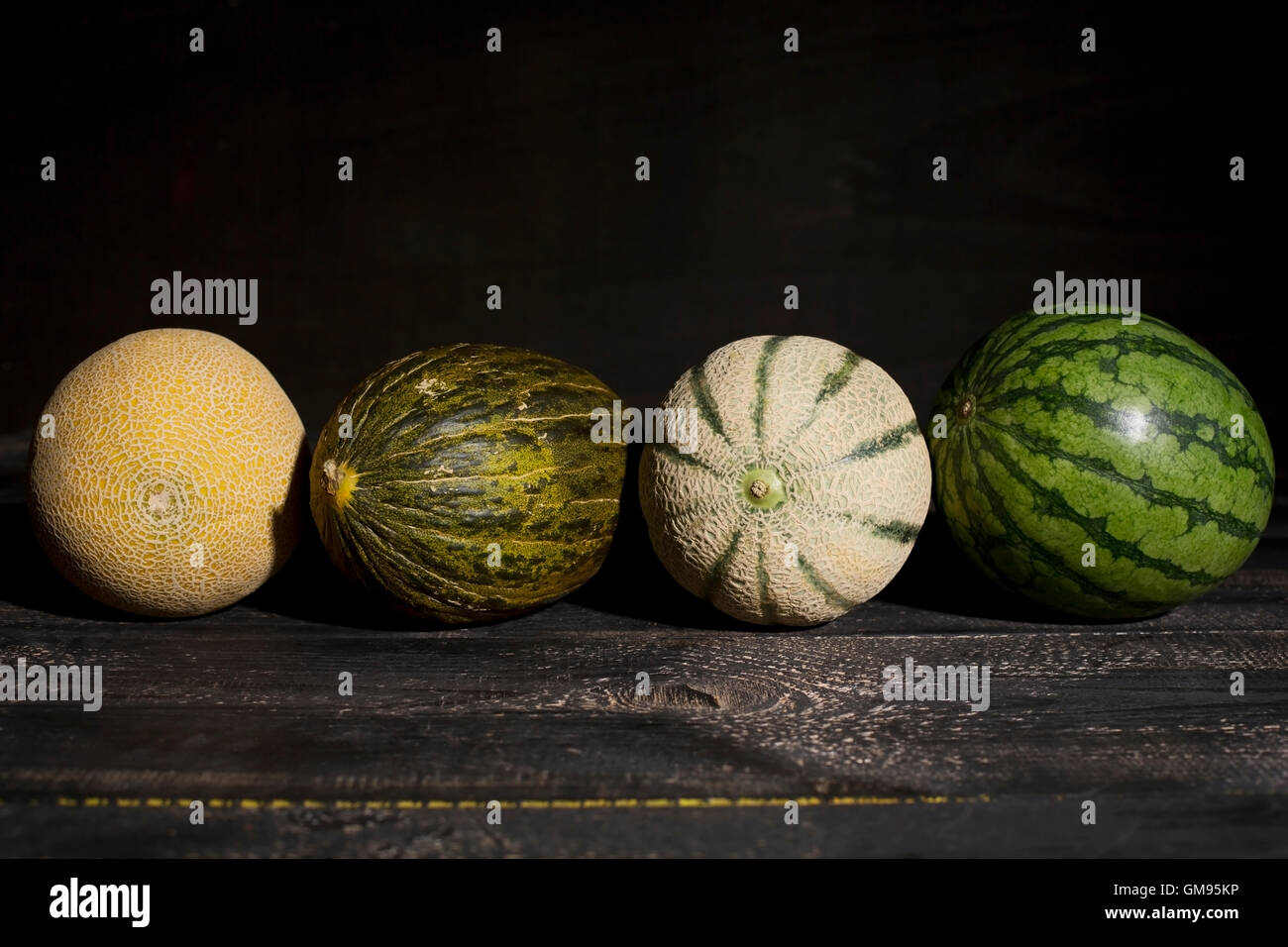 Four different melons in front of dark background Stock Photo - Alamy
