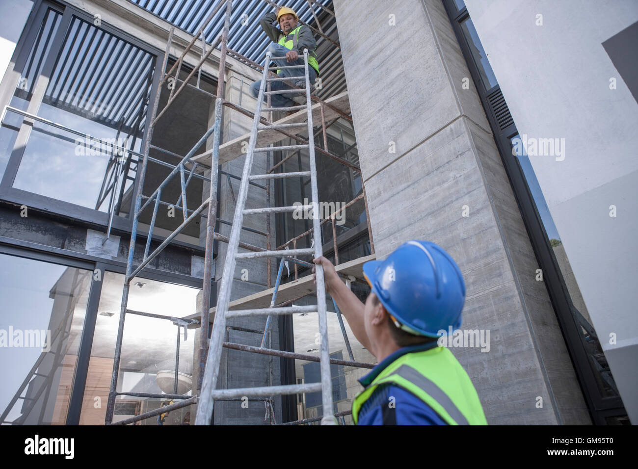 Two construction workers on scaffolding working on construction site ...
