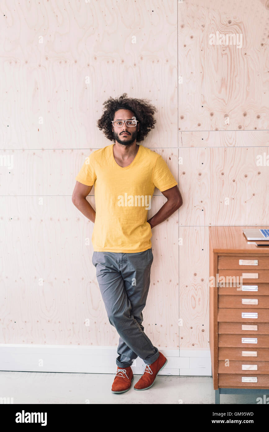 Young man leaning against wooden with hands behind back Stock Photo - Alamy