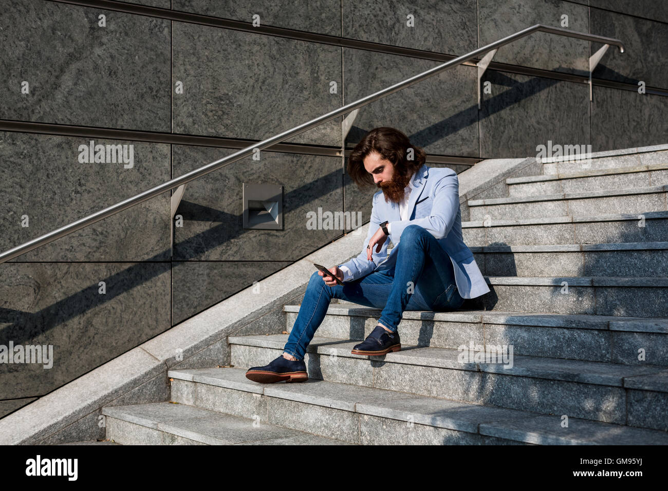 Stylish businessman using cell phone on stairs outdoors Stock Photo - Alamy
